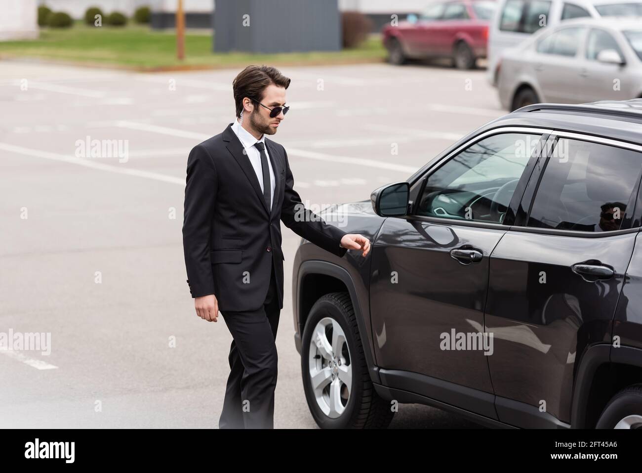 bearded bodyguard in suit and sunglasses with security earpiece walking ...