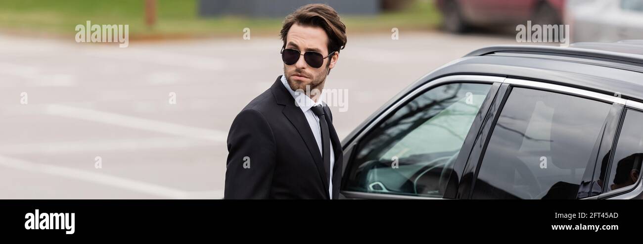 bearded bodyguard in suit and sunglasses with security earpiece near ...
