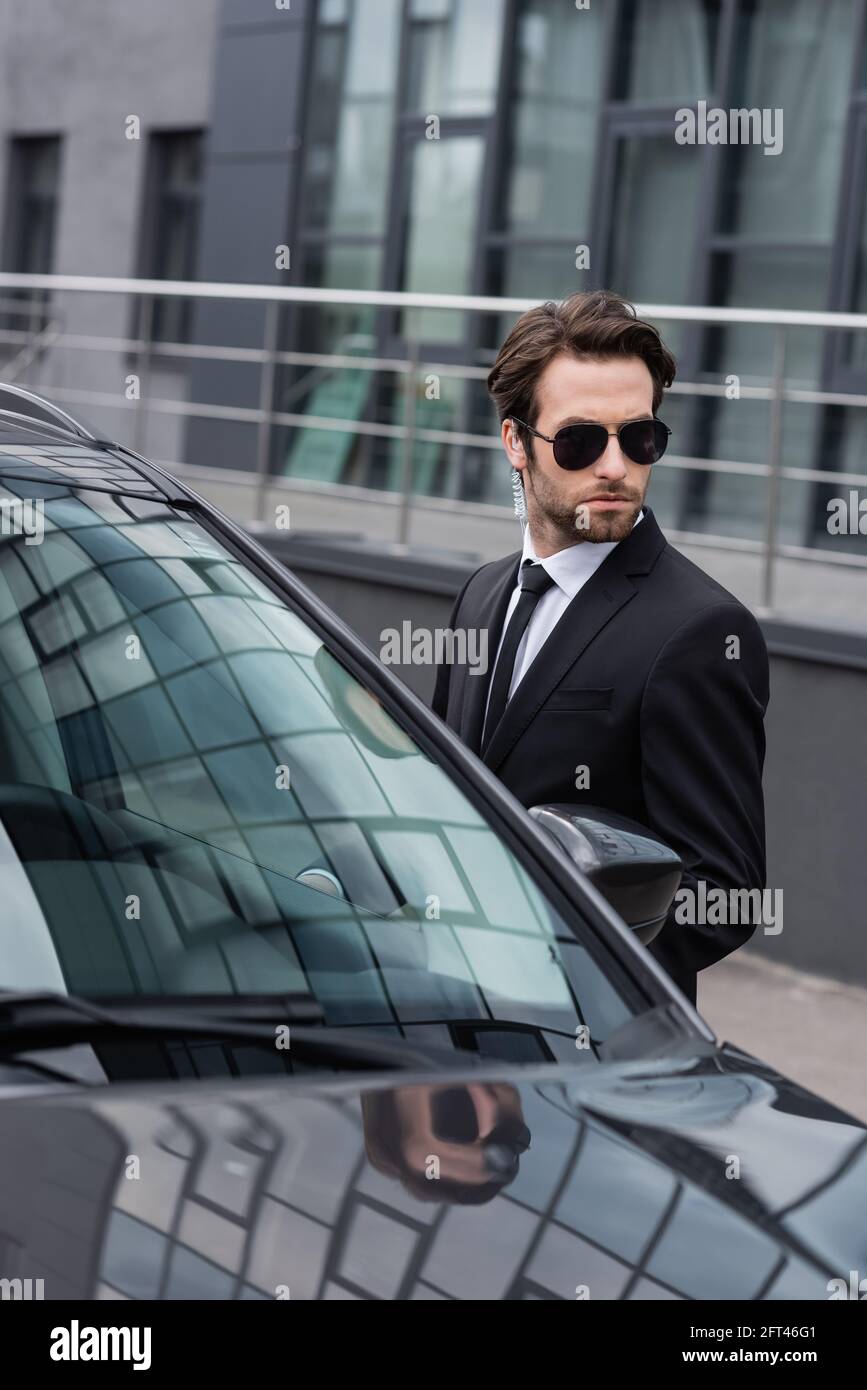 bearded bodyguard in suit and sunglasses with security earpiece near ...