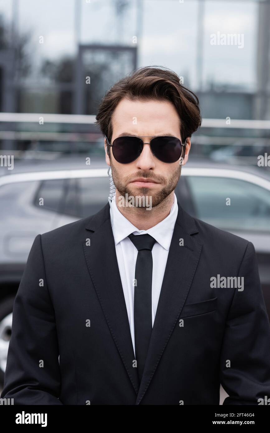 bearded bodyguard in suit and sunglasses with security earpiece near ...