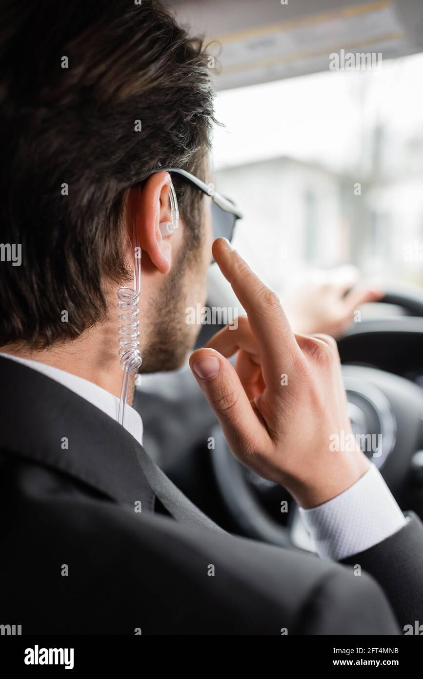 back view of bodyguard in sunglasses pointing at security earpiece ...
