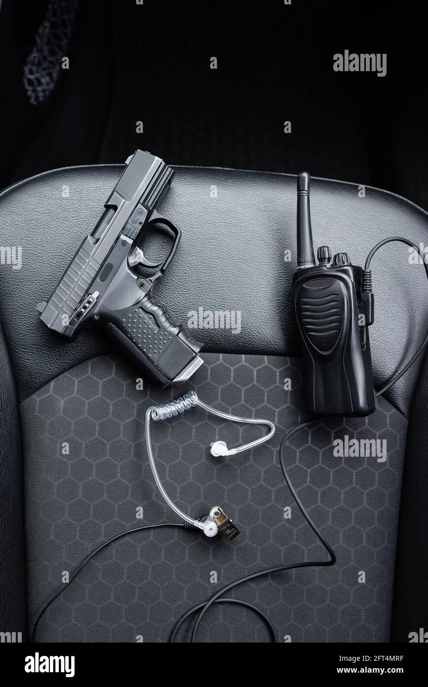 top view of walkie talkie, gun and security earpiece on car seat Stock ...