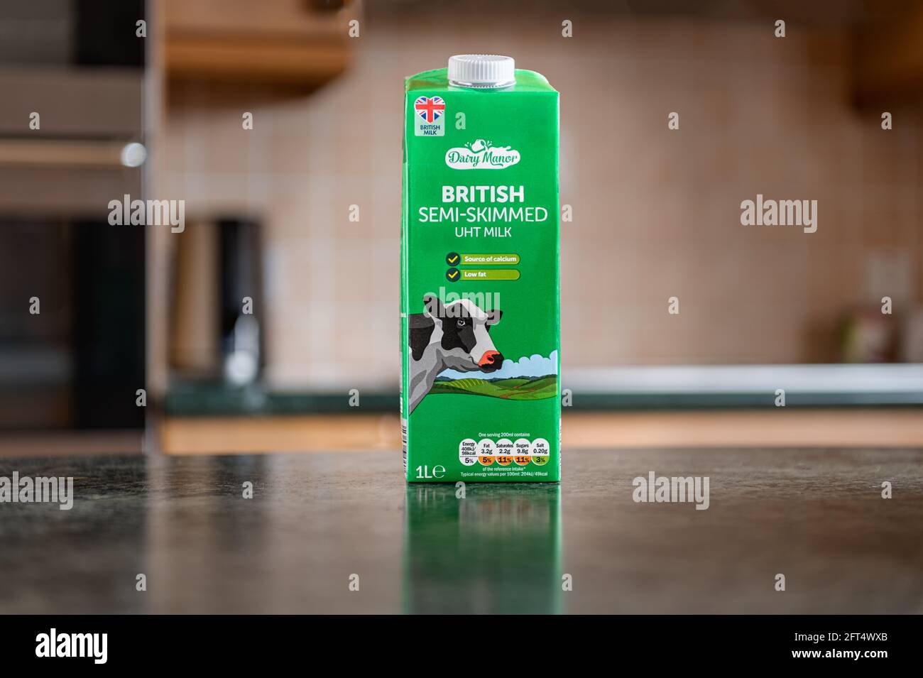 Dairy Manor Semi-Skimmed Milk Tetra Pack with a blurred kitchen in the ...