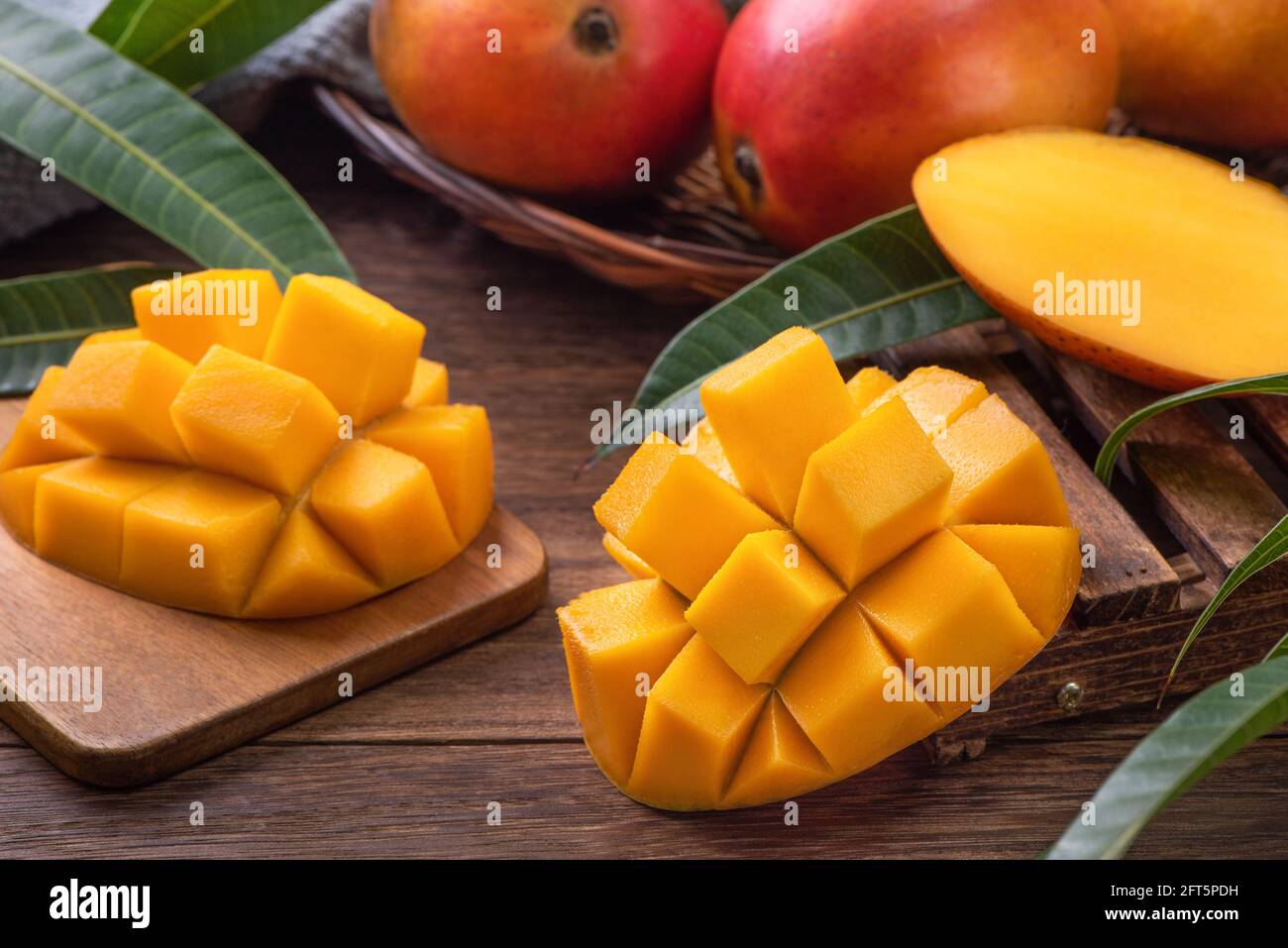 Mango. Close up of fresh ripe mango fruit with leaves over dark wooden ...