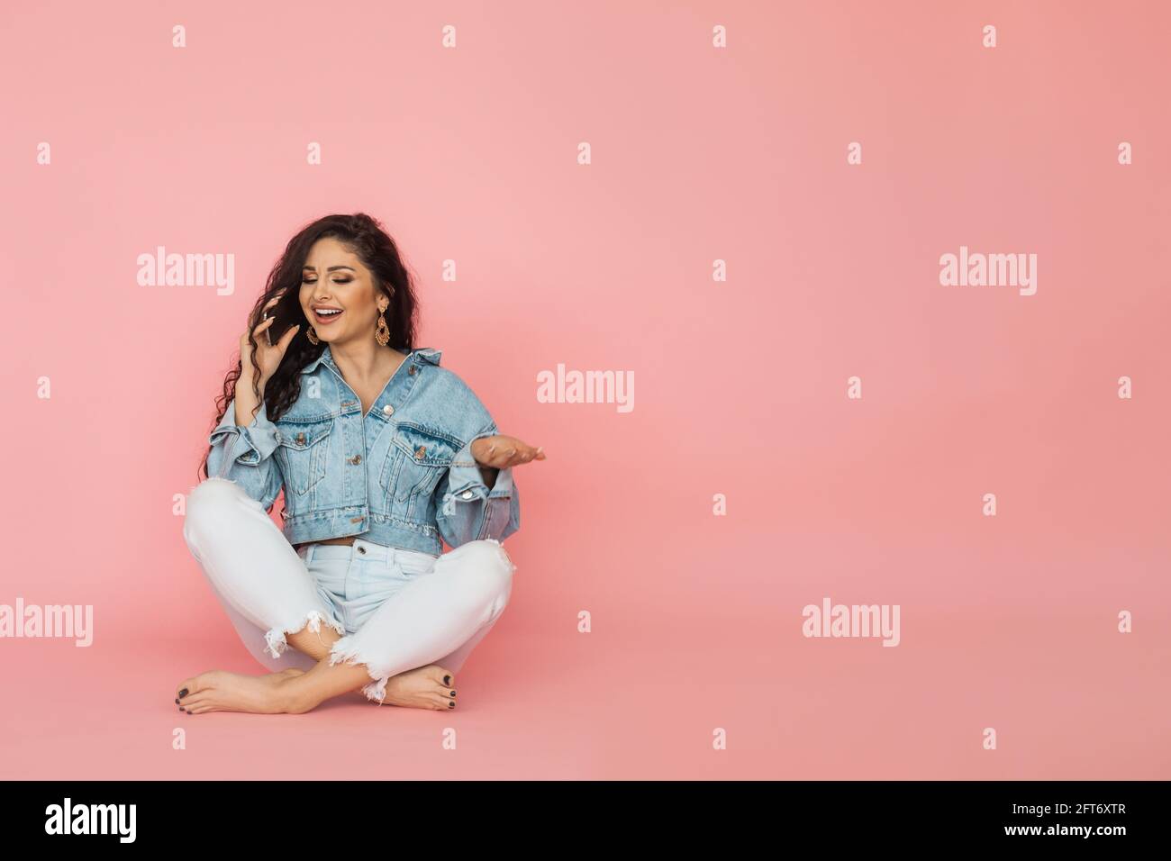Woman emotionally talking on phone sits cross-legged on floor. Photo in ...