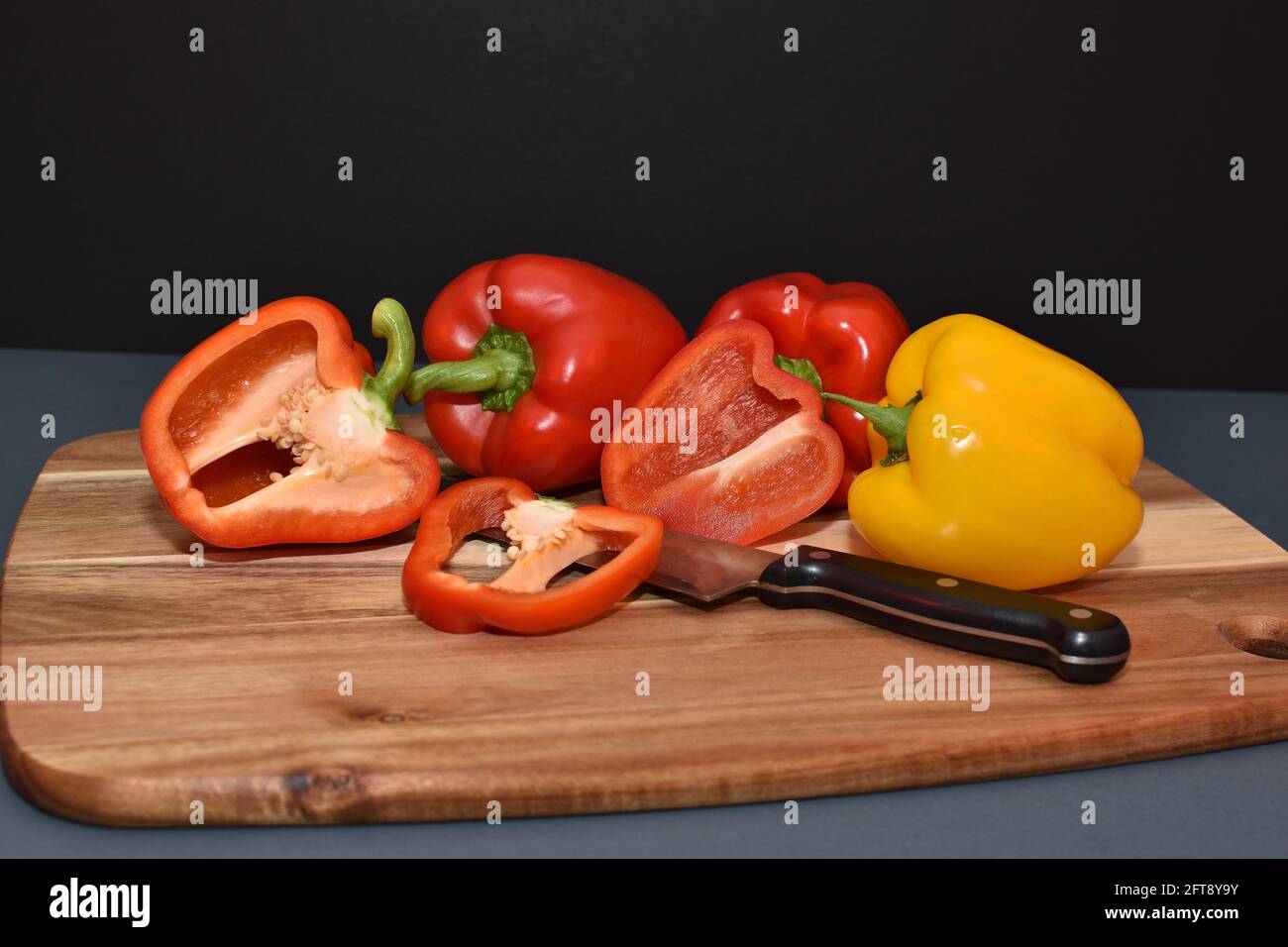 Mixed bell peppers on a chopping board with a knife, one red pepper ...