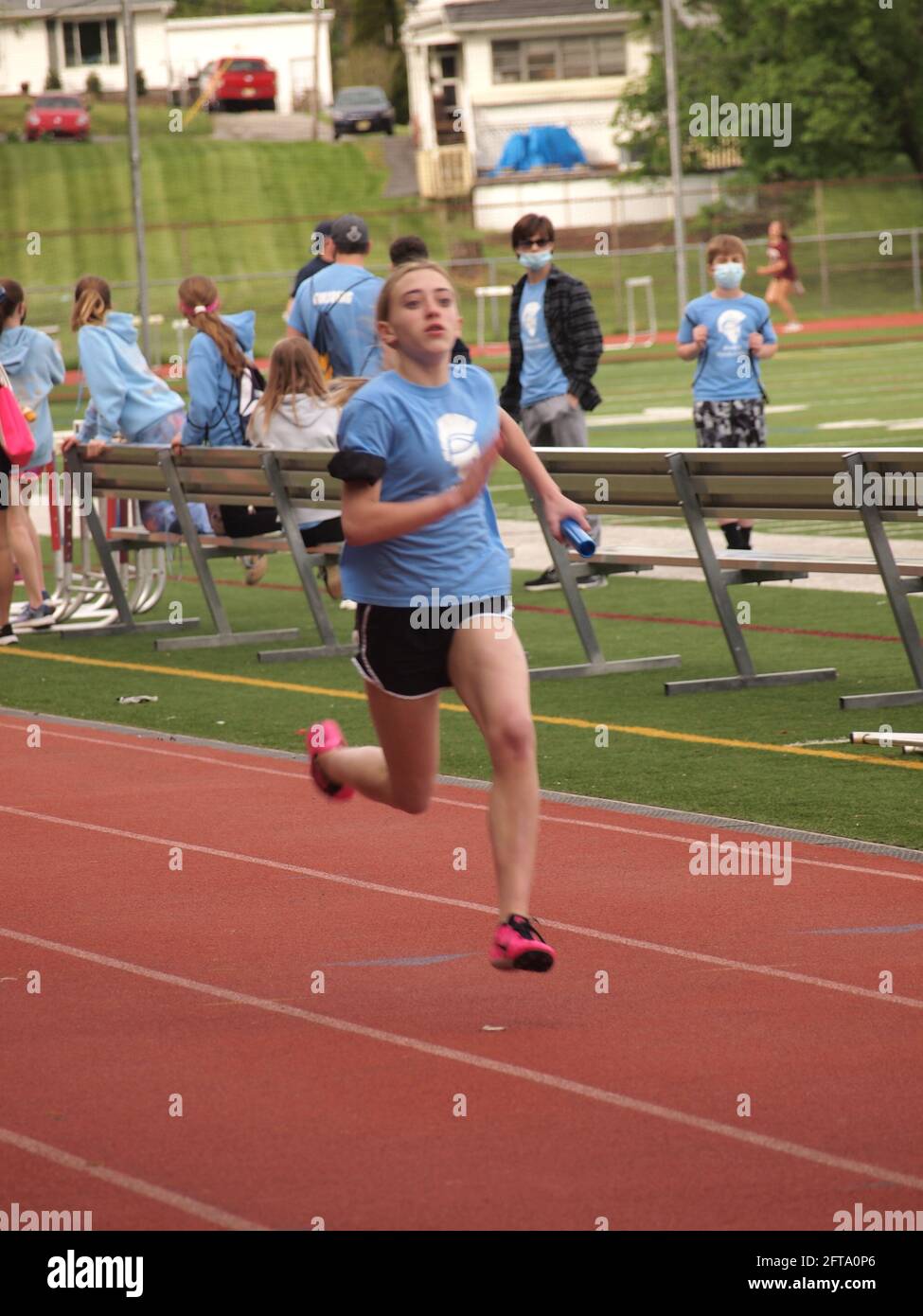 Middle school track meet with relay race hand-off and sprinting girl at ...