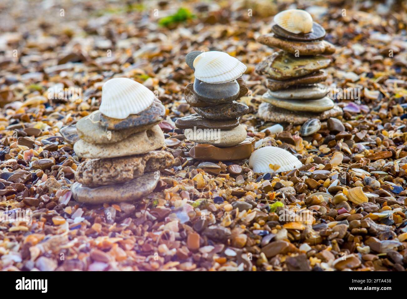 Three sea pebble turret and white shell on top. sea stones on the beach ...