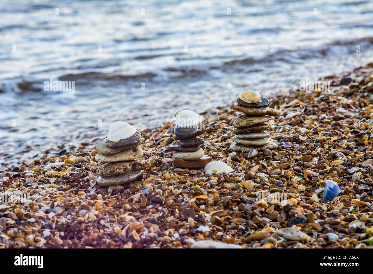 Three sea pebble turret and white shell on top. sea stones on the beach ...