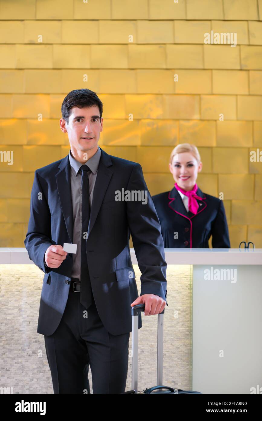 Man in Hotel check in at reception or front office being given key card ...