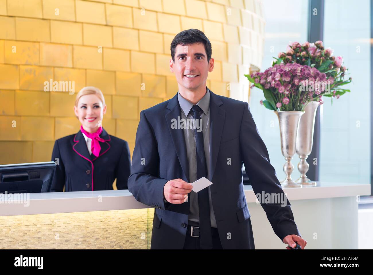 Man in Hotel check in at reception or front office being given key card ...