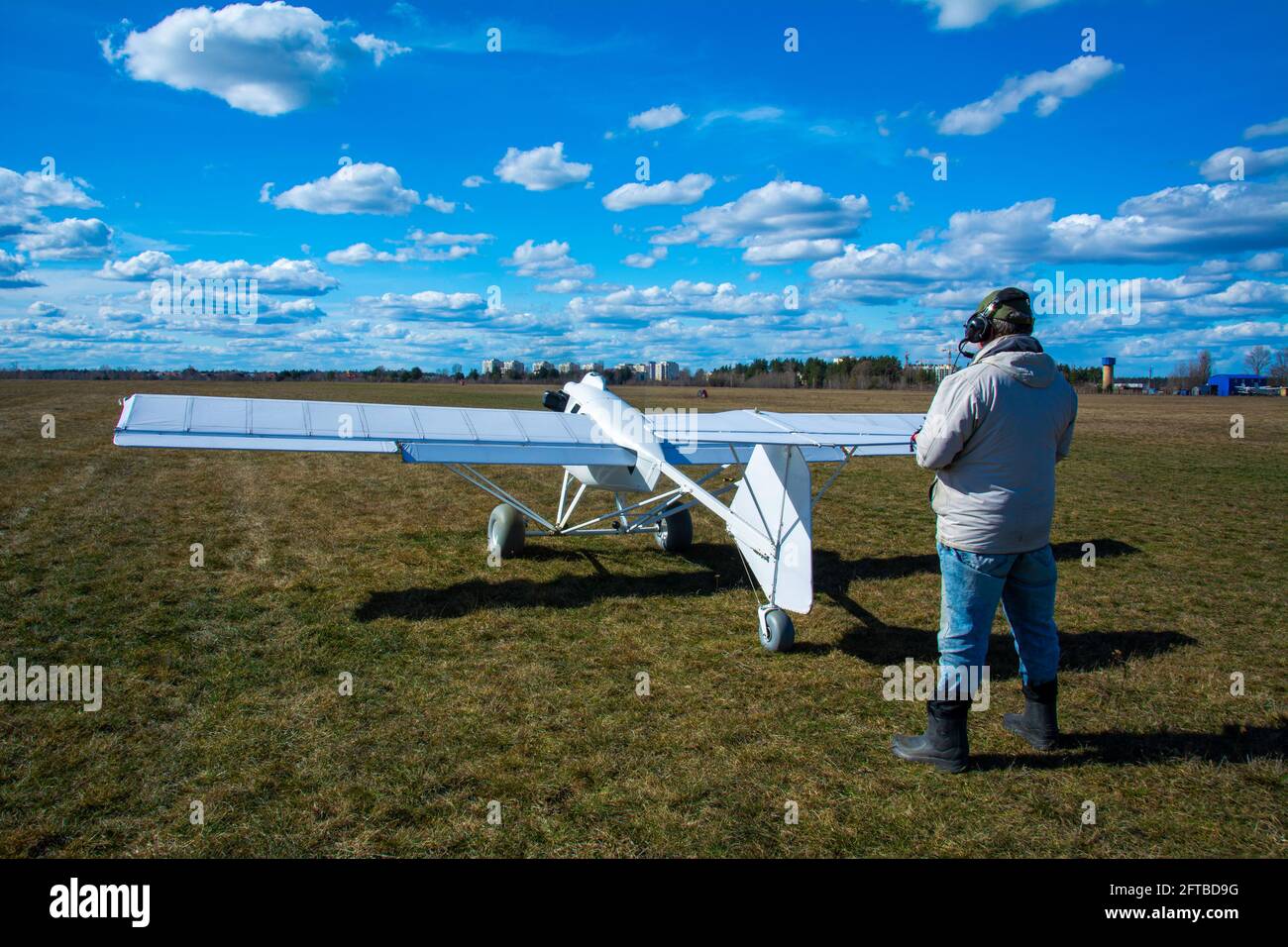An operator with an unmanned airplane on the runway. A man is flying an ...