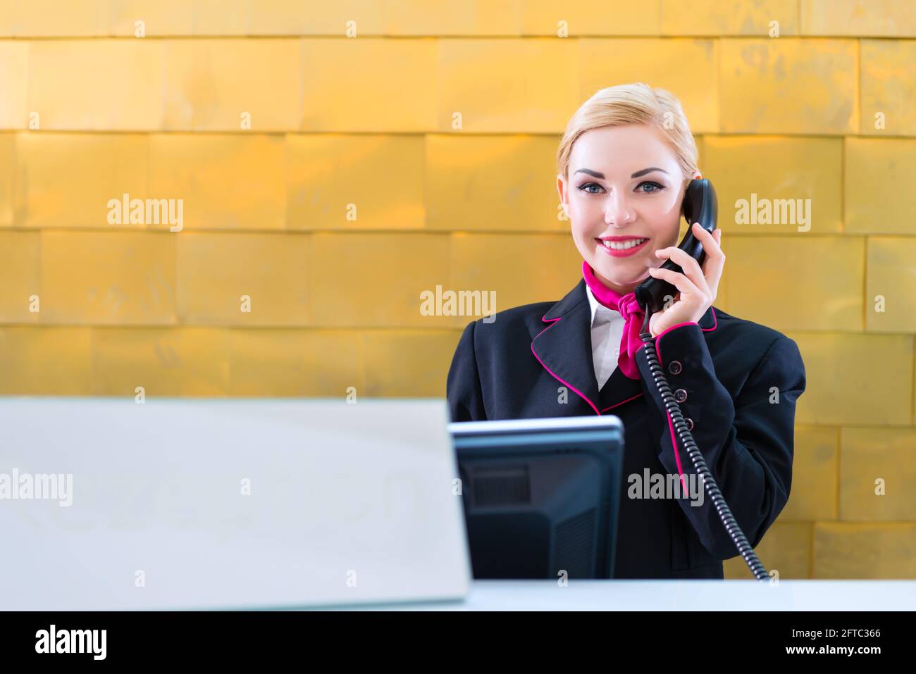 Hotel receptionist with phone on front desk Stock Photo - Alamy