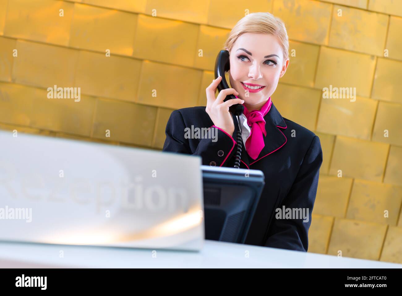 Hotel receptionist with phone on front desk Stock Photo - Alamy