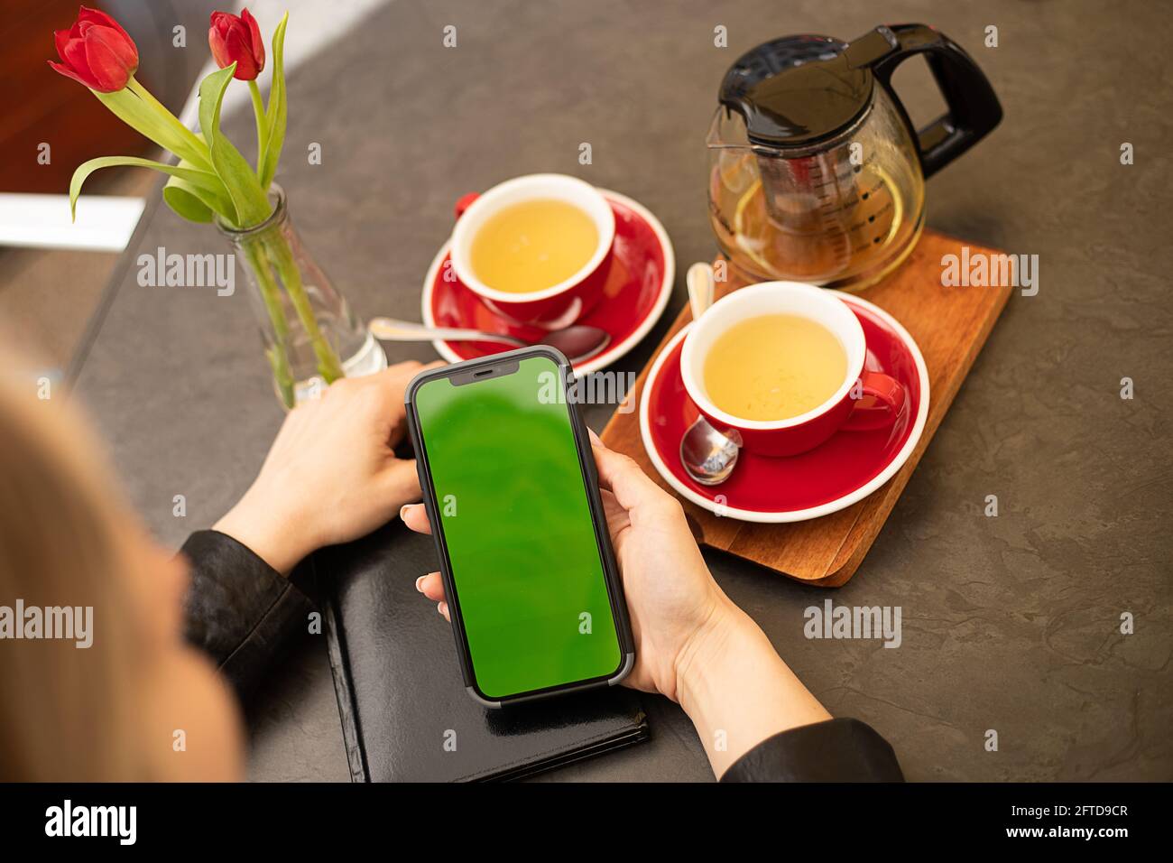 Chroma key phone screen in the hands of woman drinking tea in cafe ...