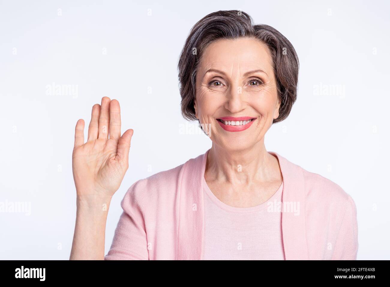 Photo of aged cheerful woman happy positive smile waving hand hello hi ...