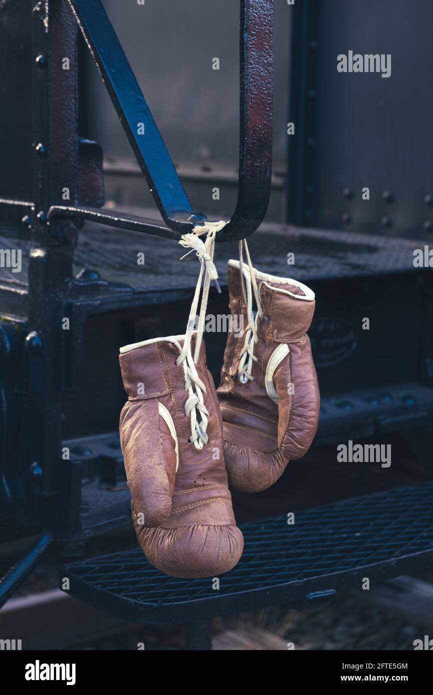 two brown boxing gloves hanging form steel handle Stock Photo - Alamy