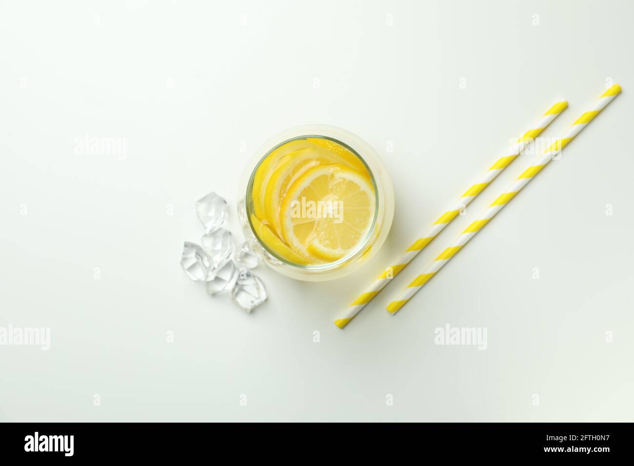Glass of lemonade, straws and ice cubes on white background Stock Photo ...