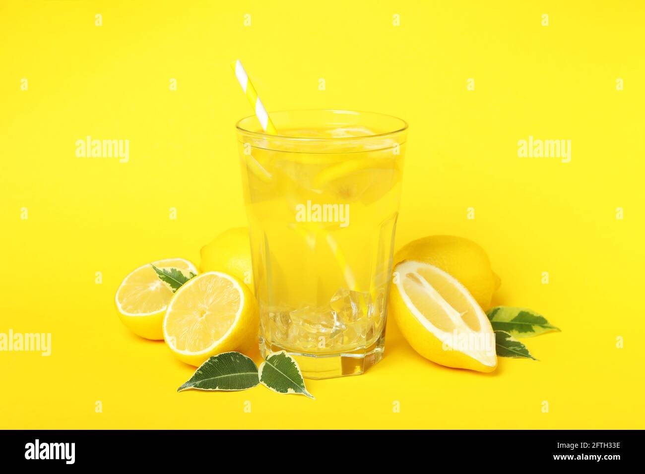 Glass of lemonade and lemons on yellow background Stock Photo - Alamy