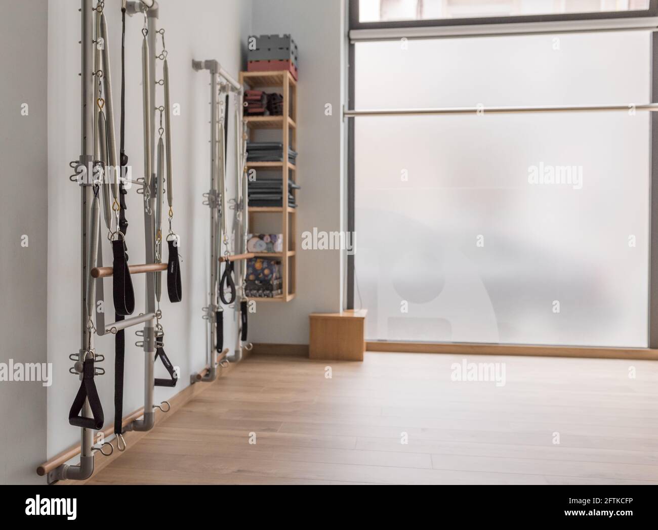 Side view of a pilates studio with two machines and a shelf. Wooden ...