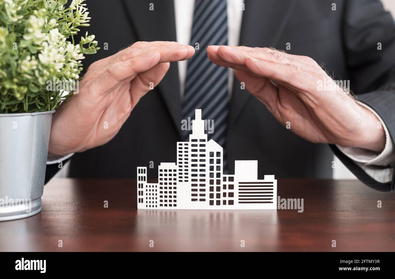 Insurer protecting an office building with his hands Stock Photo - Alamy