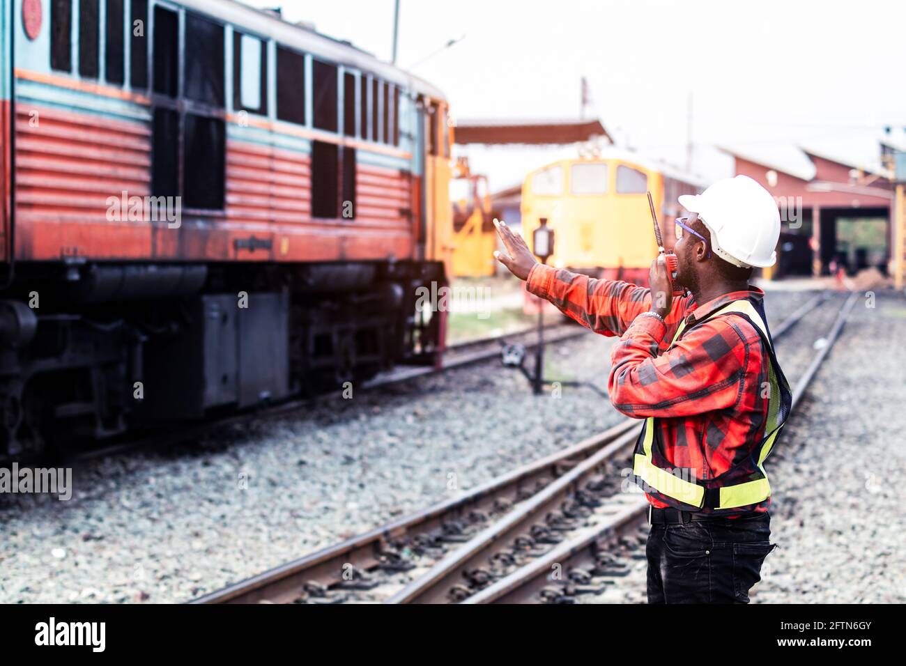 African engineer raised a hand to control a the train on railway with ...