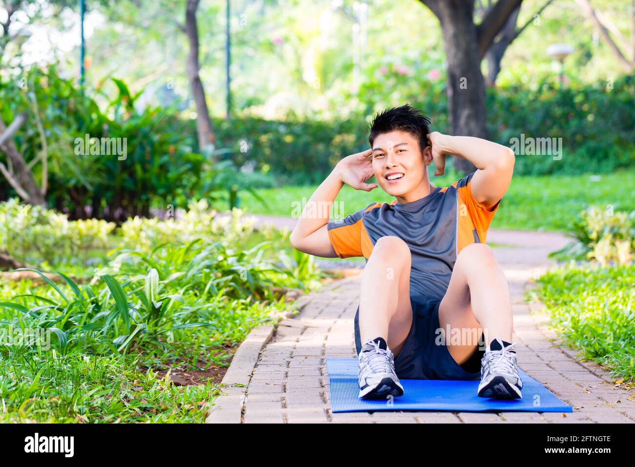 Asian man doing crunches for six pack training in park Stock Photo - Alamy