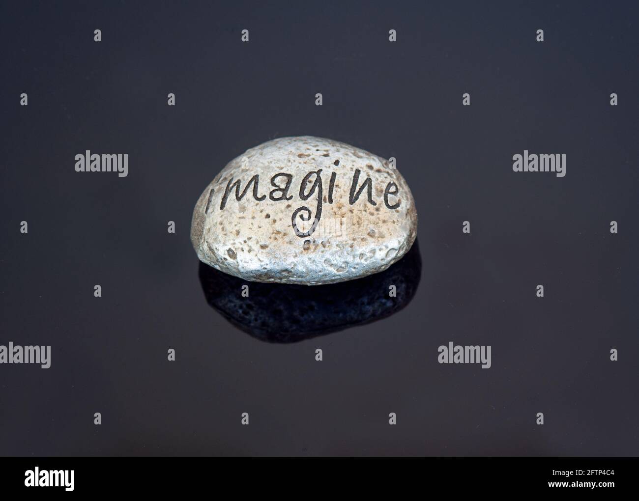 Painted rock imagine word on a shiny black background. The rock is a ...