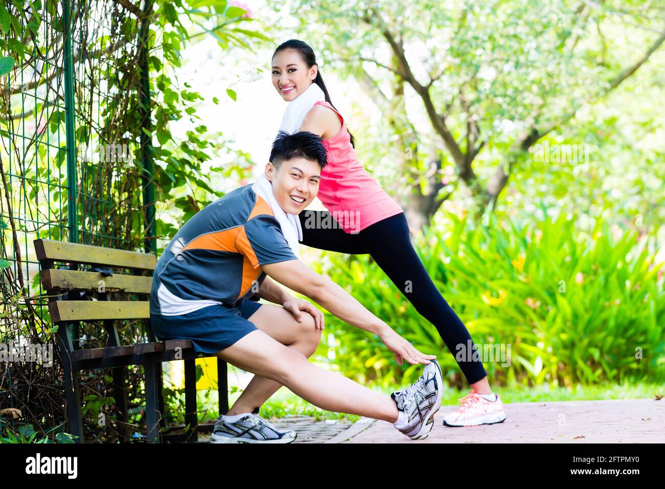 Asian Chinese man and woman stretching muscles on park bench Stock ...