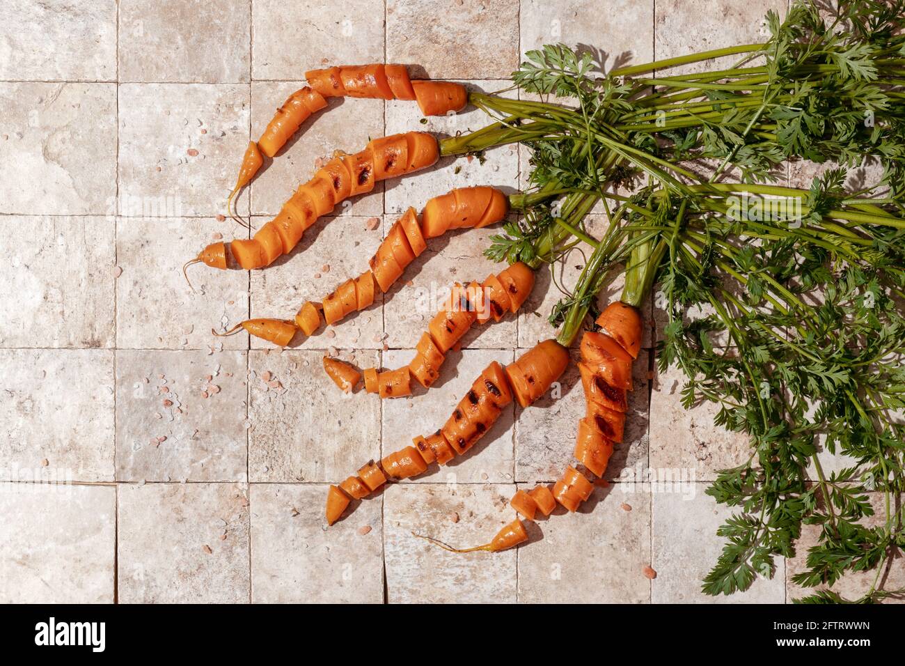 Bunch of fresh sliced carrot roots with green leaves on stone tales top ...
