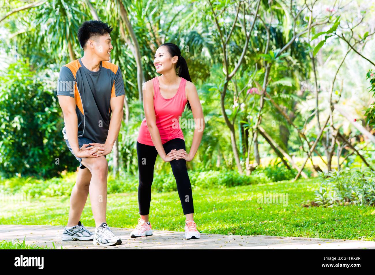 Asian Chinese man and woman stretching muscles in park for sport ...