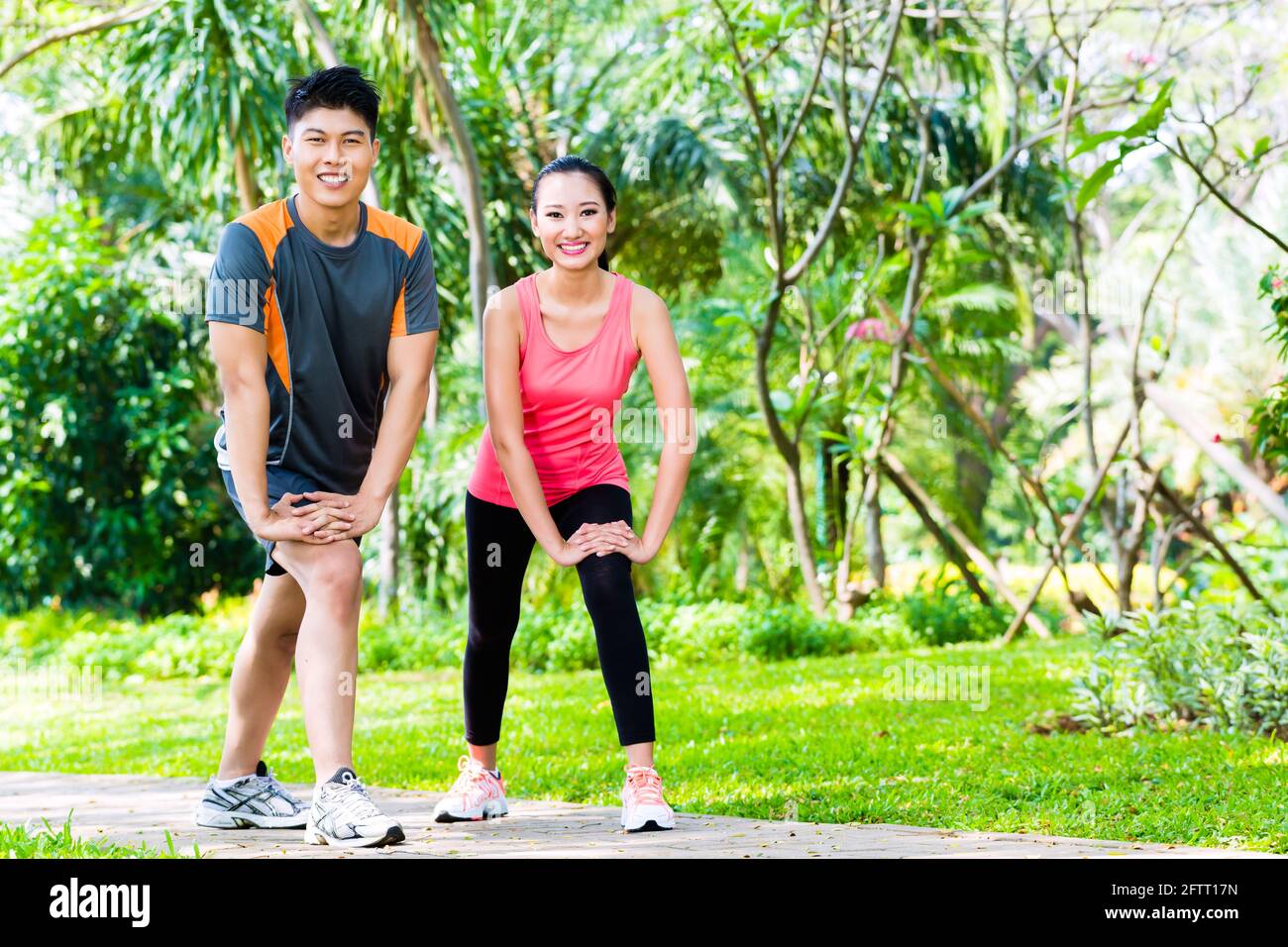 Asian Chinese man and woman stretching muscles in park for sport ...