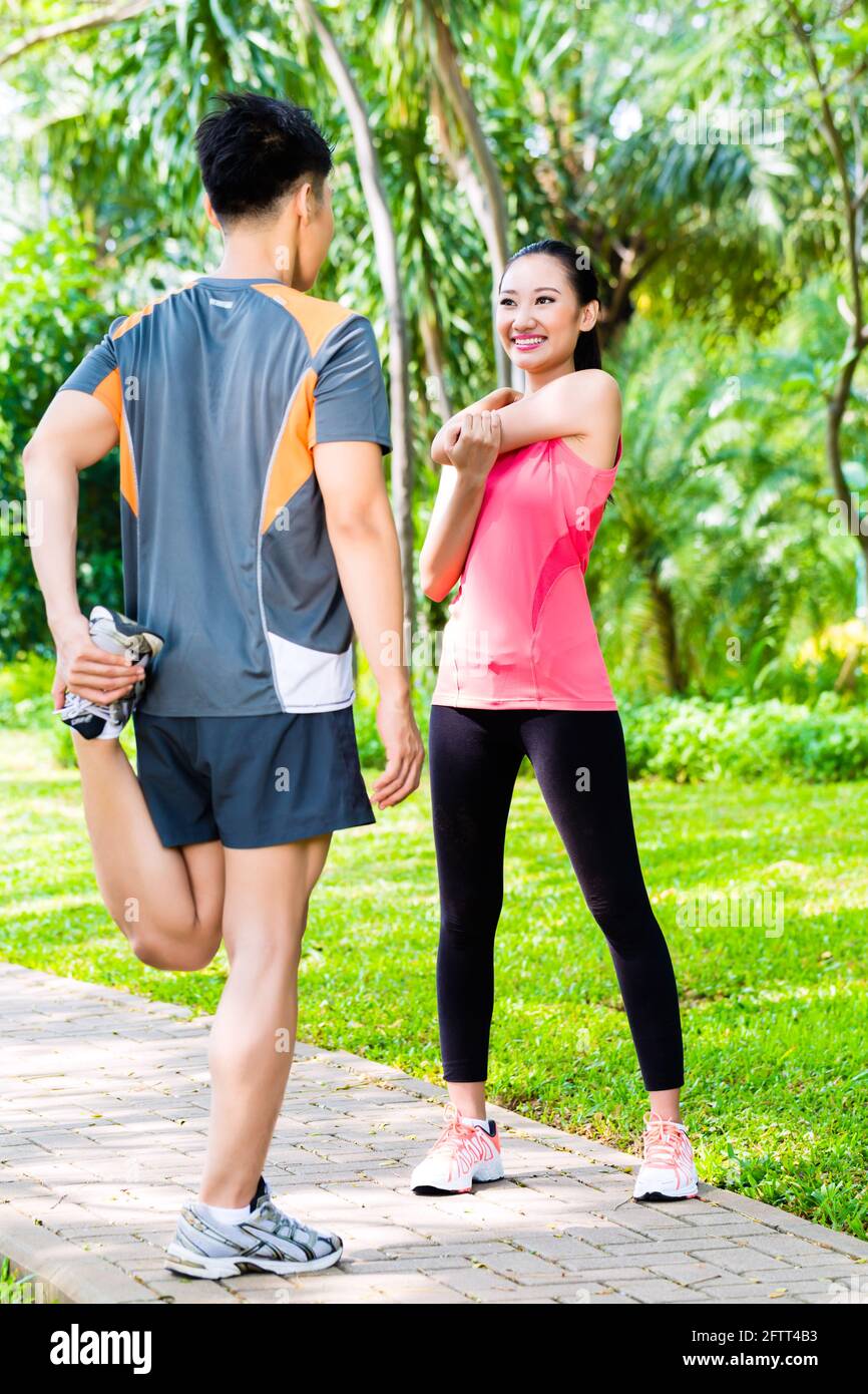 Asian Chinese man and woman stretching muscles in park for sport ...