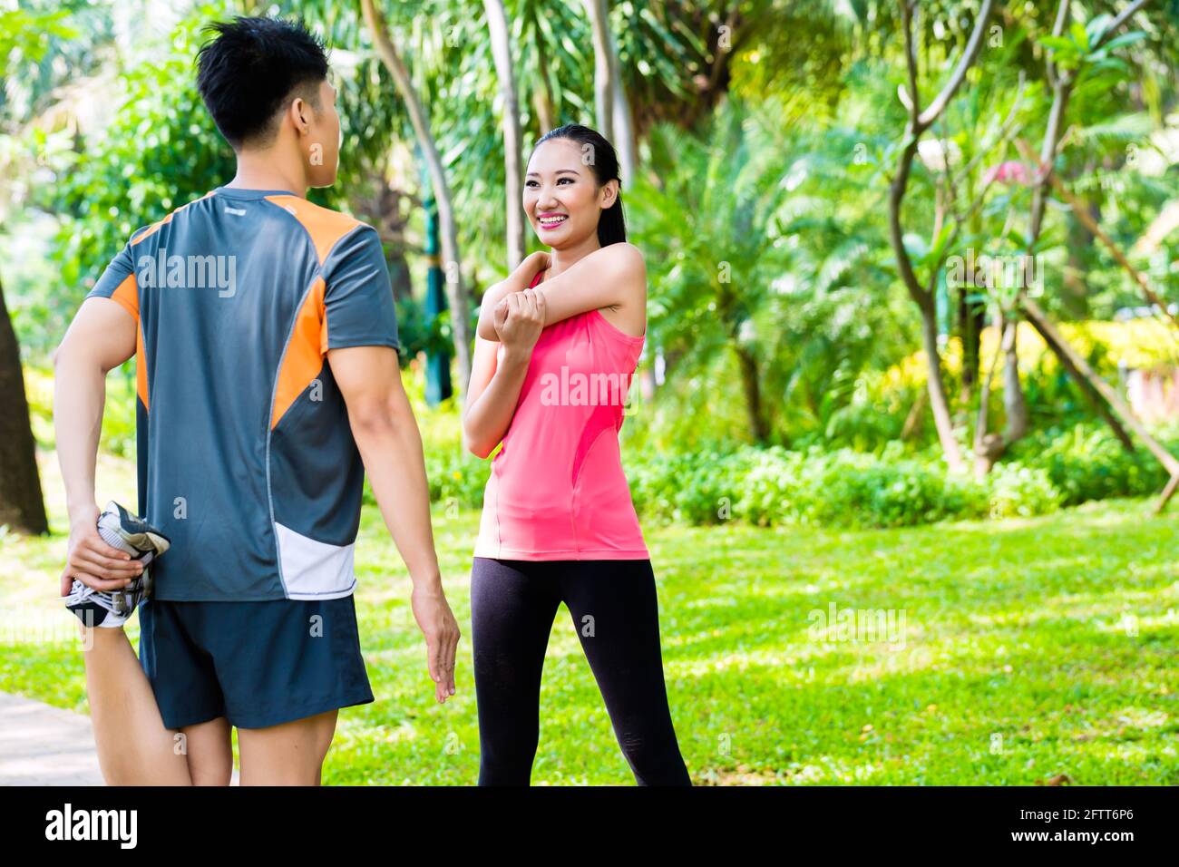 Asian Chinese man and woman stretching muscles in park for sport ...