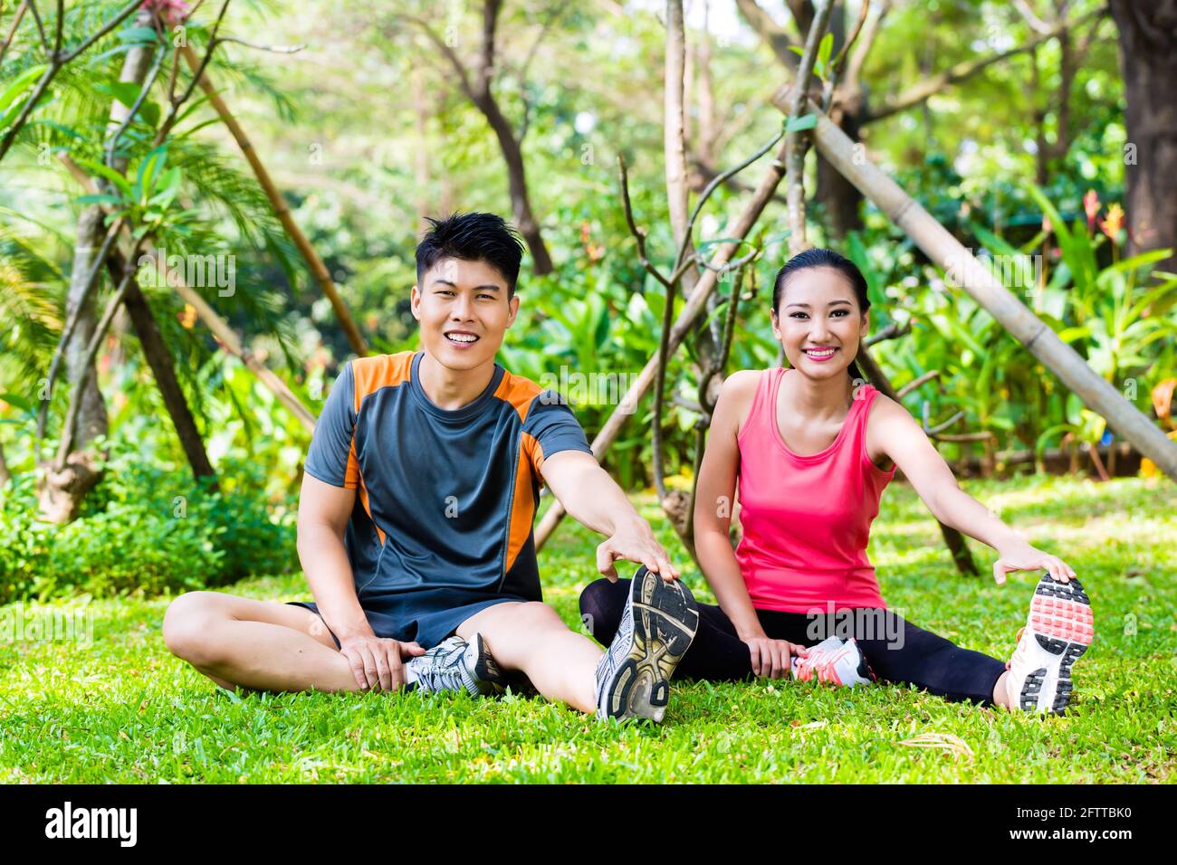 Asian Chinese man and woman stretching muscles in park for sport ...