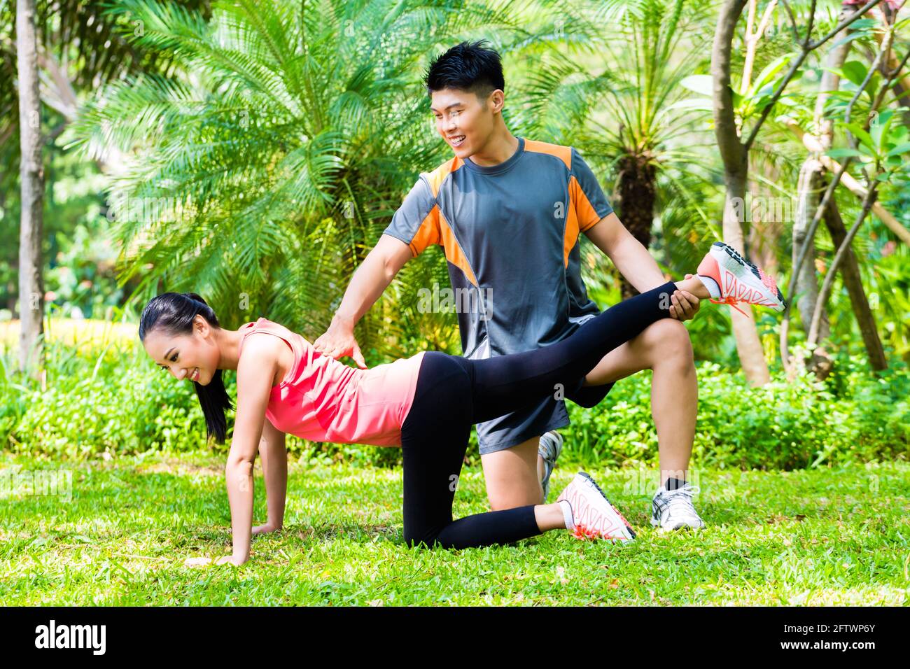 Asian Chinese personal trainer helping woman with stretching exercises ...