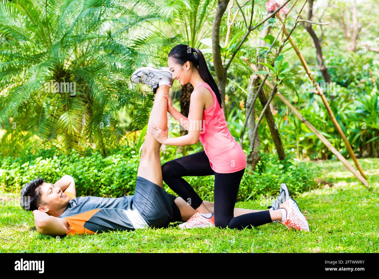 Asian Chinese personal trainer helping woman with stretching exercises ...