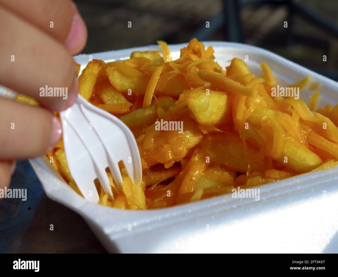 Take away cheesey chips being eaten with plastic fork Stock Photo - Alamy
