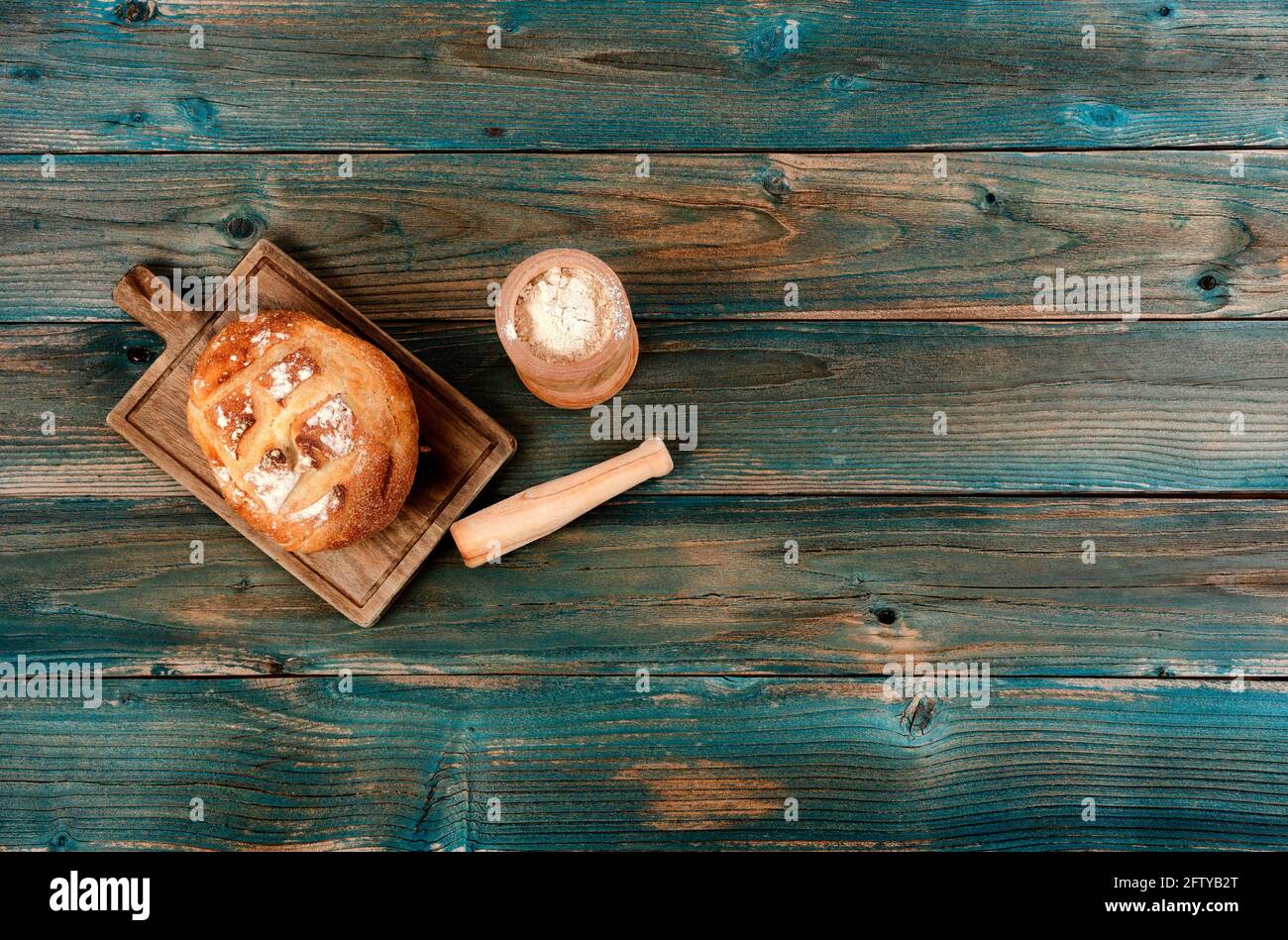 Freshly baked whole loaf of sourdough, flour, rolling pin and server on ...