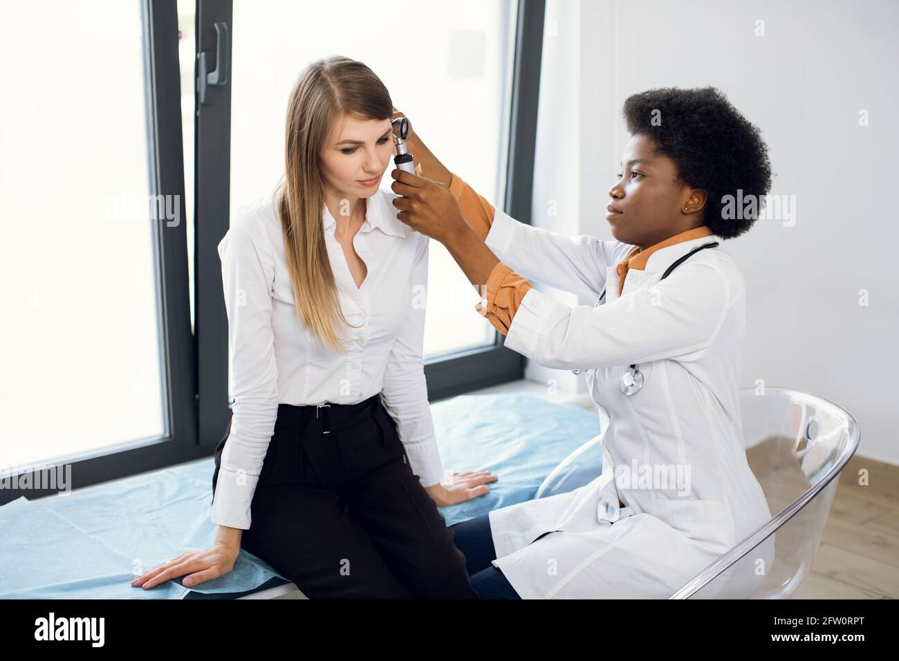 Young attractive Caucasian woman getting medical ear exam at modern ...