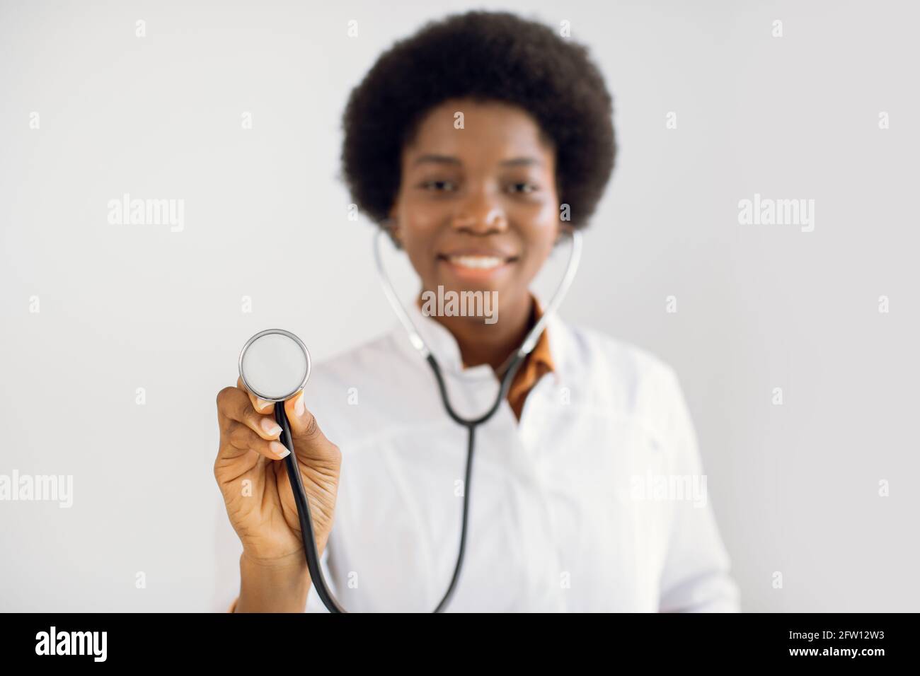 Focus on stethoscope. Blurred close up portrait of happy African ...