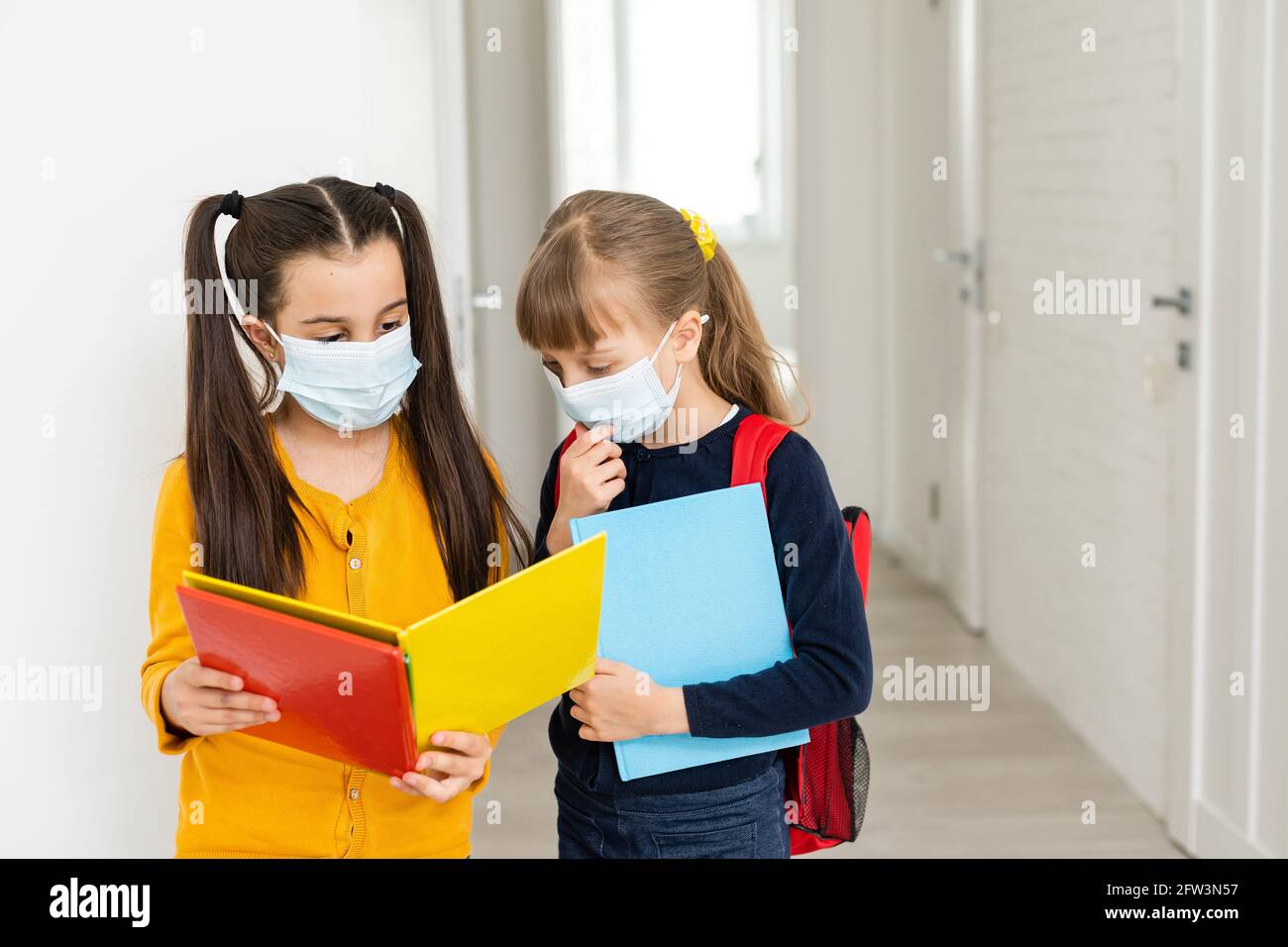 Cute little girls of primary hug each other with the mask on. School ...