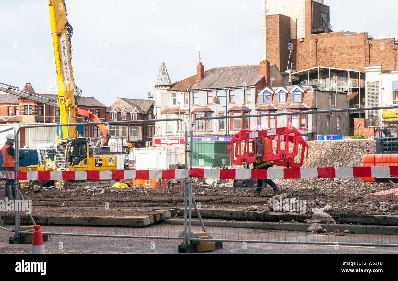 Man carrying safety barriers behind safety fencing on demolition ...