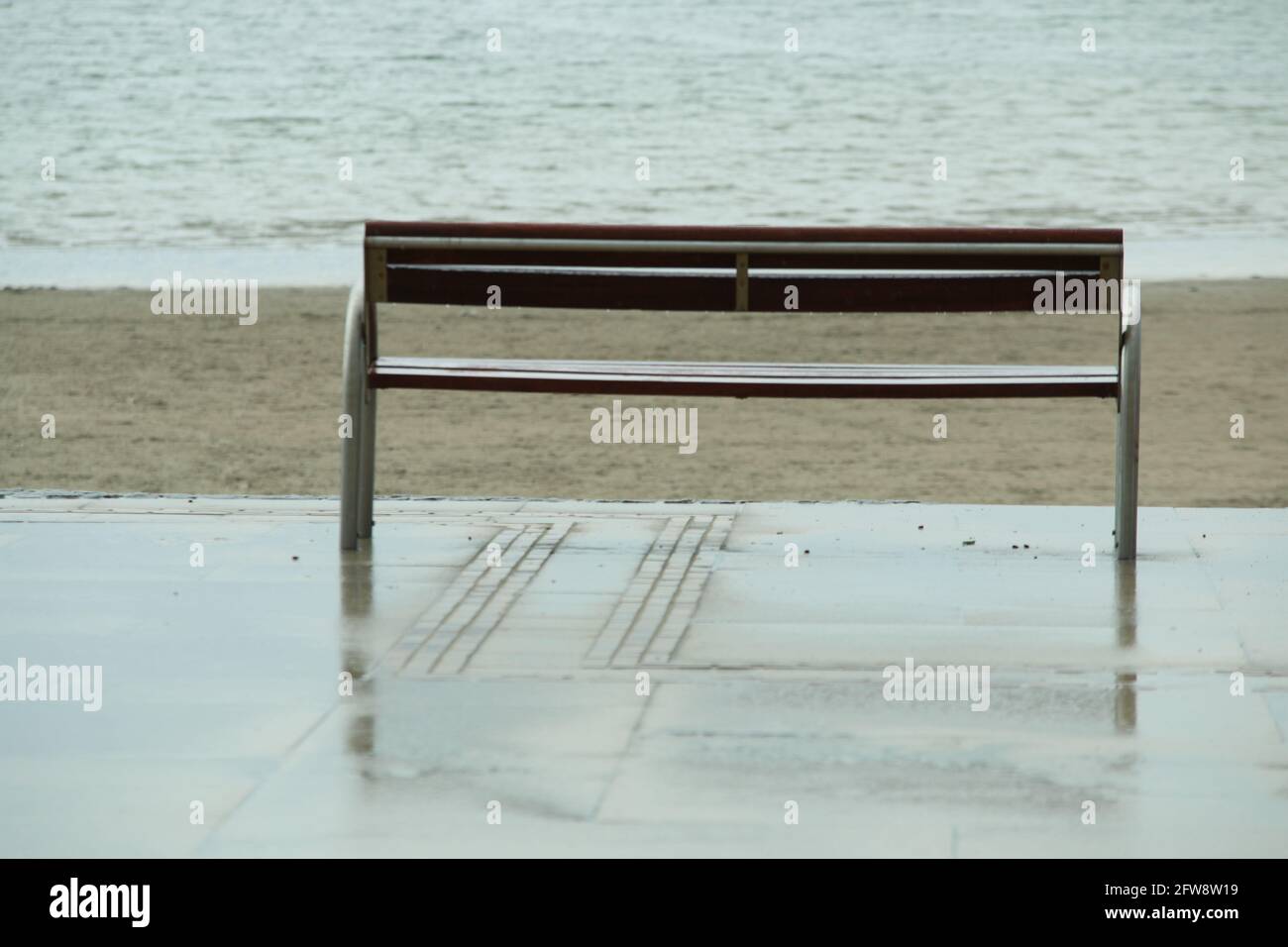 Wooden bench in front of the beach and the ocean on a rainy day Stock ...