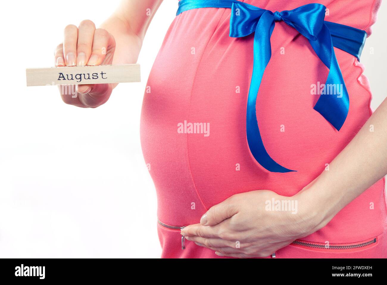 Pregnant woman in pink dress with blue ribbon showing word august ...