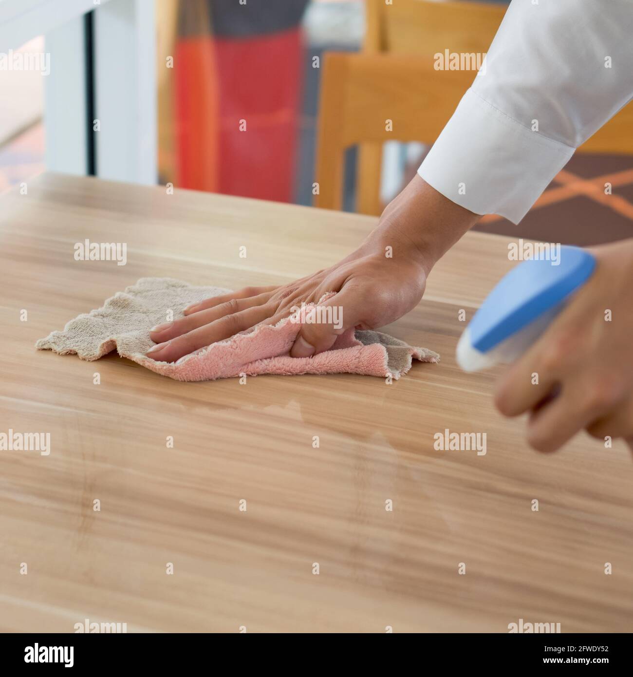 Closeup waiter's hand use a liquid cleaner and a towel to wipe off the ...