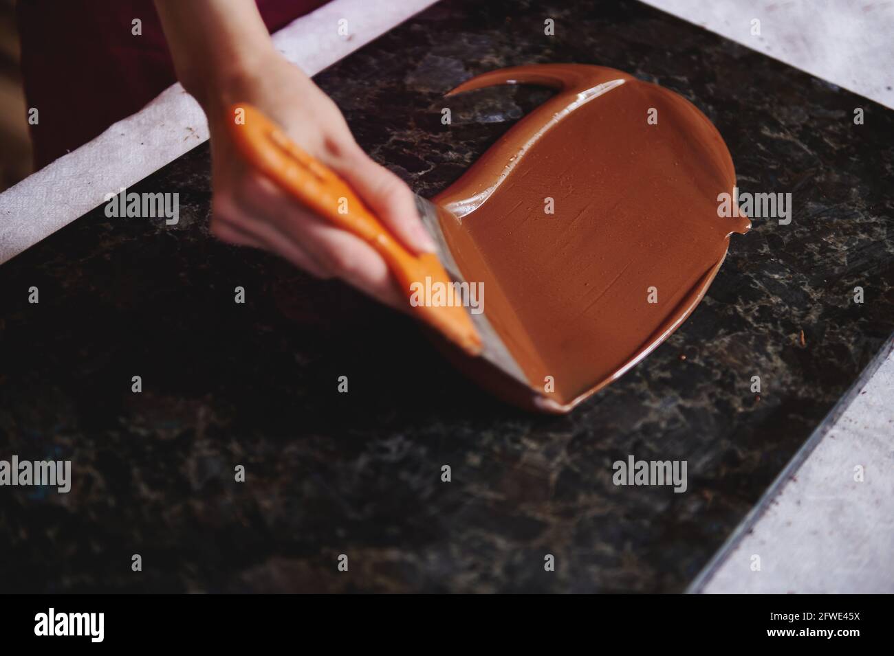Closeup of woman's hand tempering melted chocolate on a marble surface ...