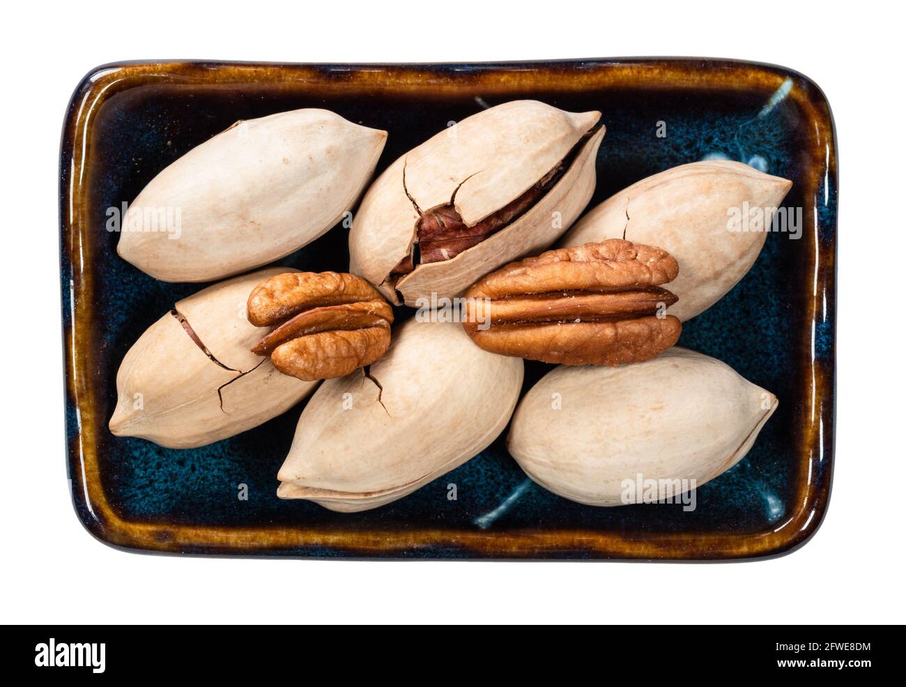 top view of shelled and unshelled pecan nuts in bowl cutout on white ...