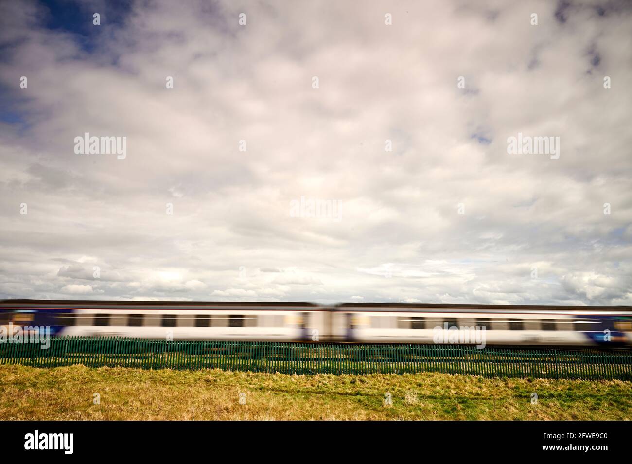 Passenger train passing through fields in rural setting Stock Photo - Alamy