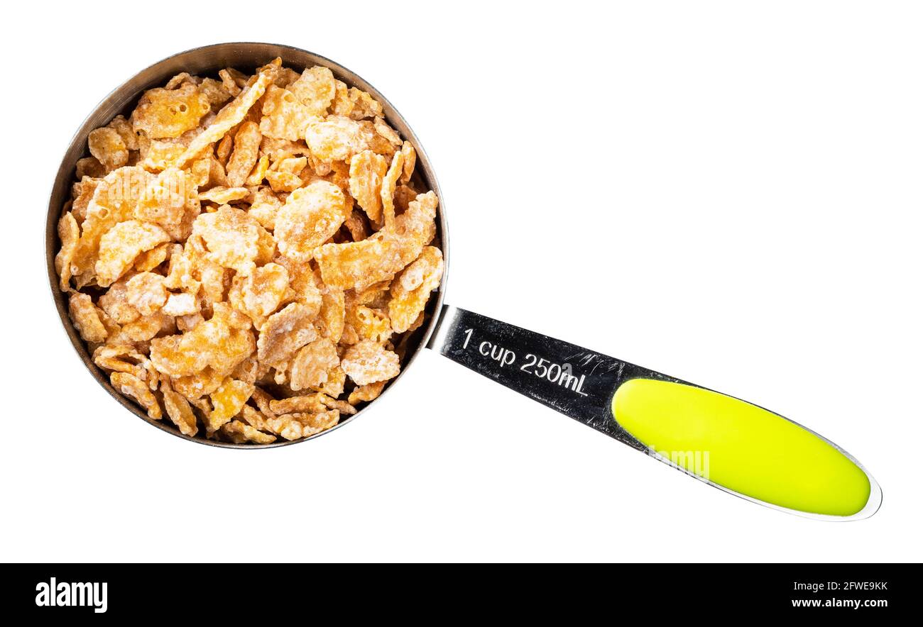 top view of sugar-coated cornflakes in measuring cup cutout on white ...